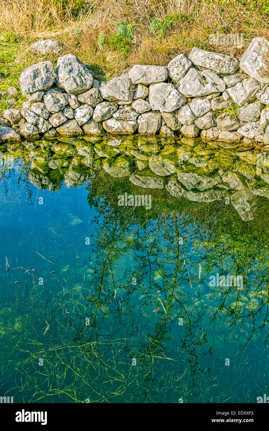 Ancient water trough with surrounding nature reflecting in the water at ...