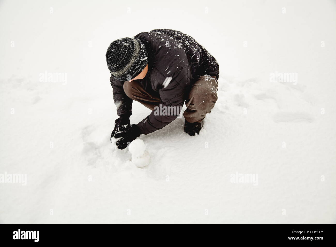 Young adult male in snow storm making snow ball Stock Photo - Alamy