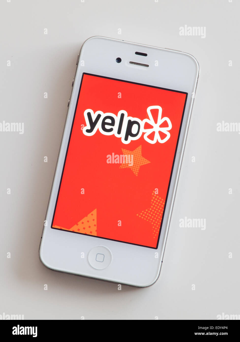 The homescreen and logo of the Yelp mobile app on a white Apple iPhone ...