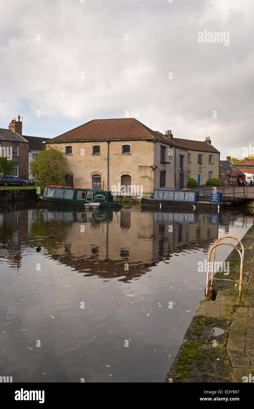 Renovated historic warehouse building and 2 moored boats, reflected in ...
