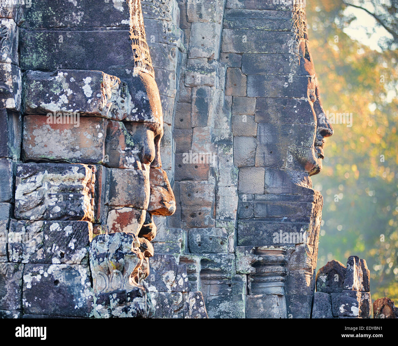 Bayon temple carving of the face with sunbeams through the rainforest ...