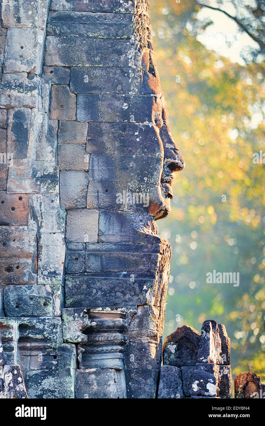 Bayon temple carving of the face with sunbeams through the rainforest ...