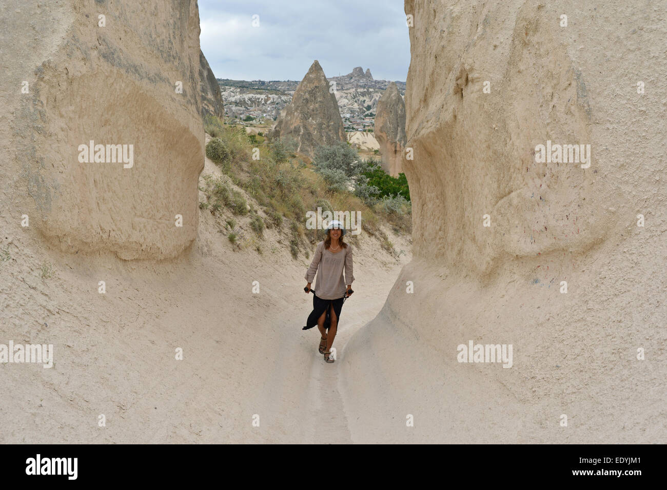 The woman dressed in skirt is walking through rocks in Cappadocia ...