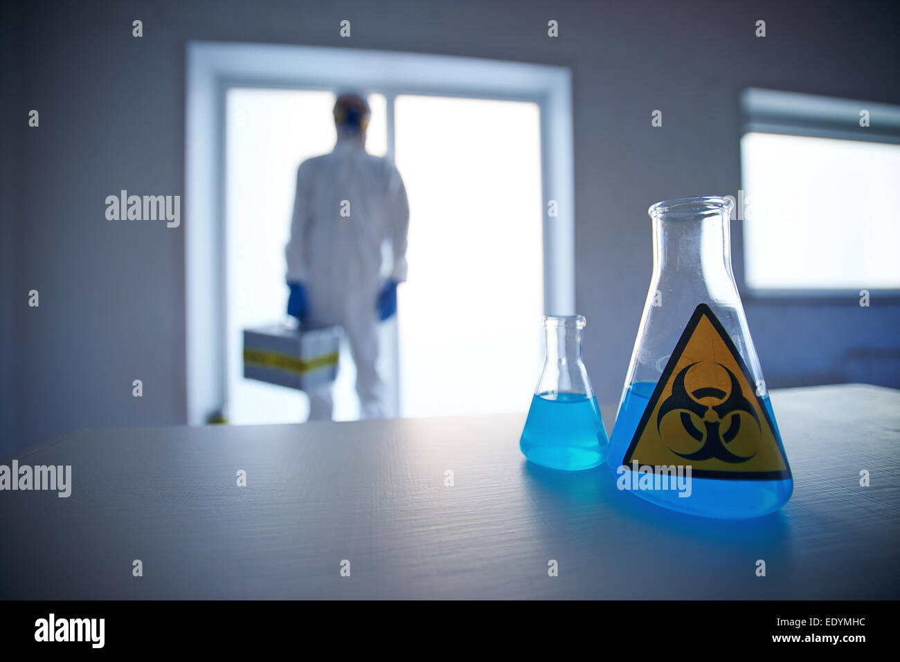 Close-up of two flasks with blue biohazard liquid with scientist on ...