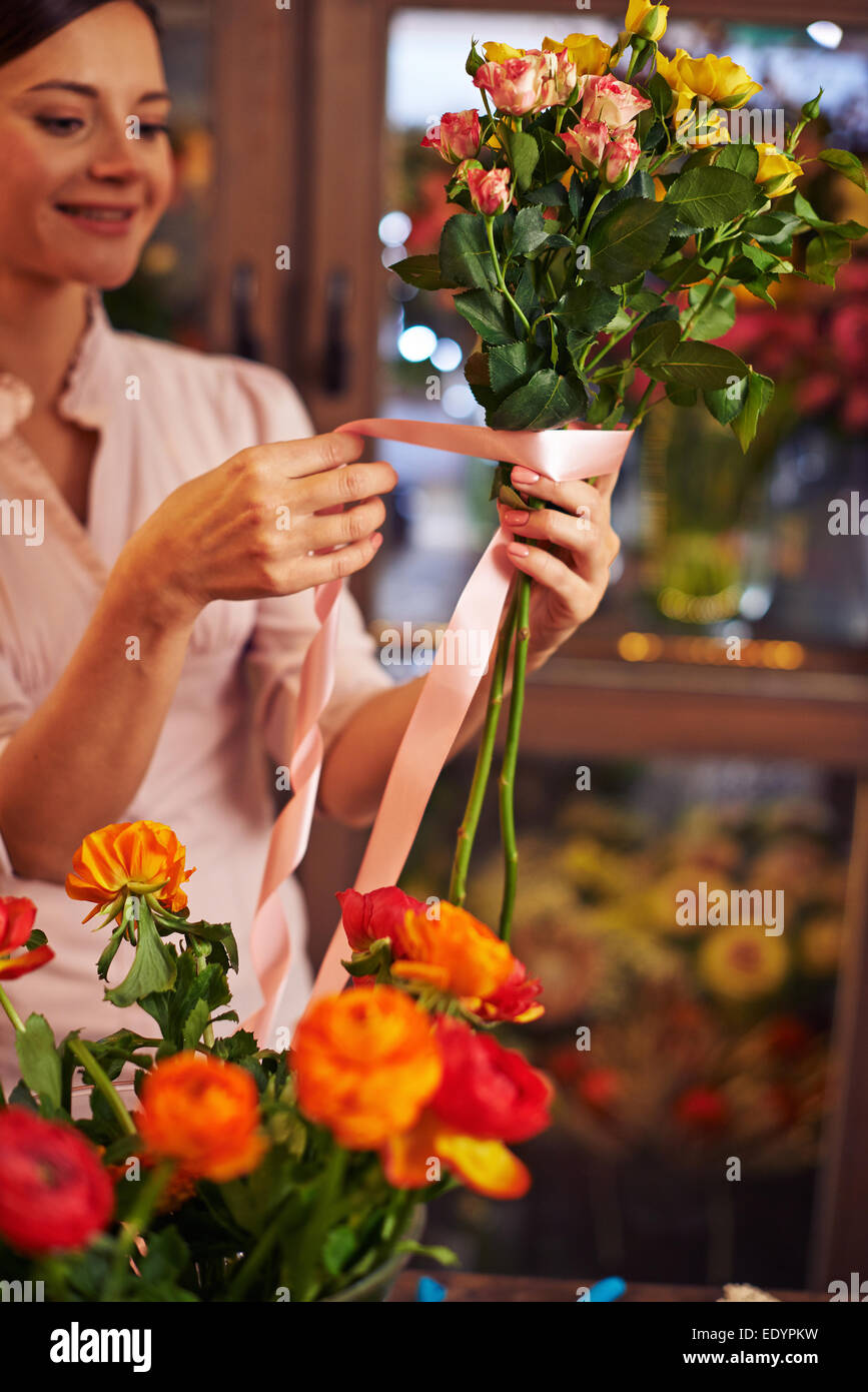 Young woman banding rose bouquet with a ribbon Stock Photo - Alamy
