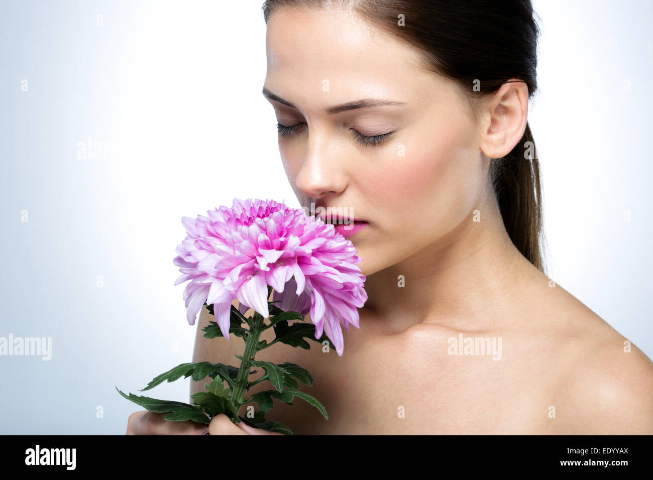 Beautiful woman smelling flowers over gray background Stock Photo - Alamy