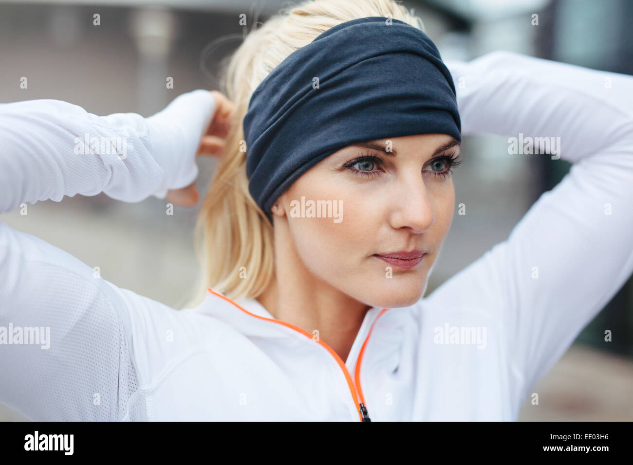 Close-up of young female athlete tying up hair before a run. Sporty ...