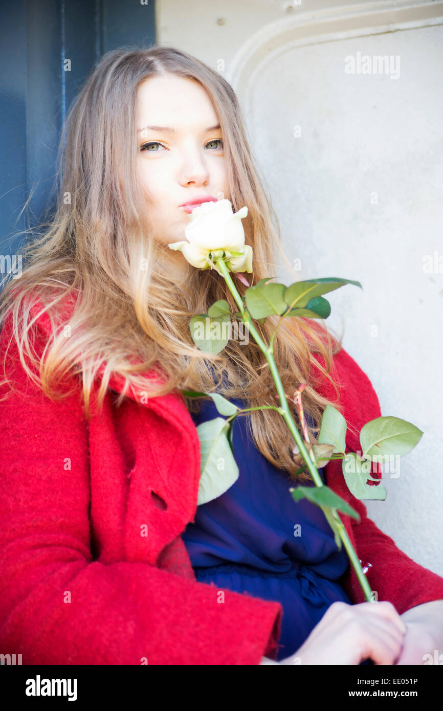Woman smelling white rose next to stain door Stock Photo - Alamy