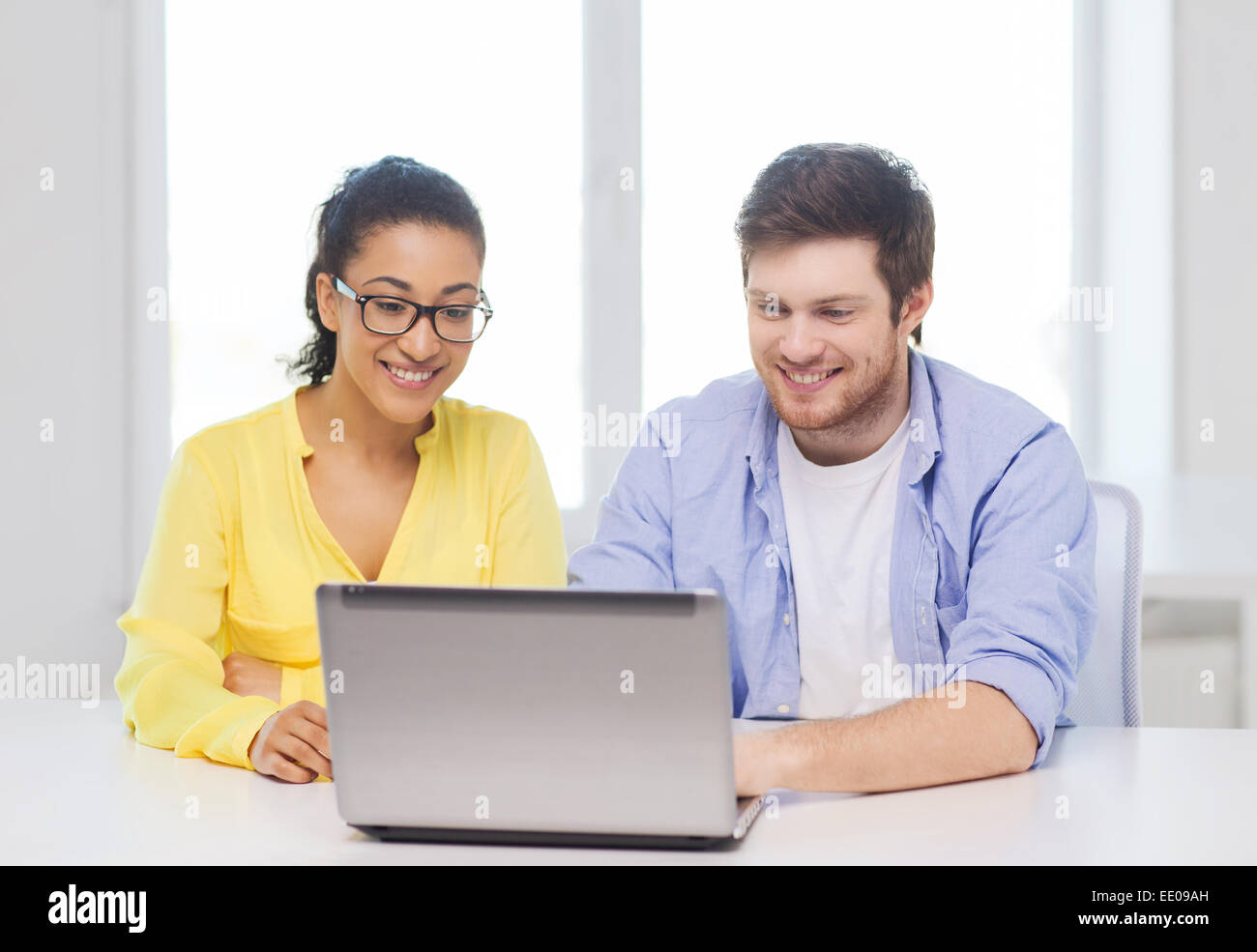 two smiling people with laptop in office Stock Photo - Alamy