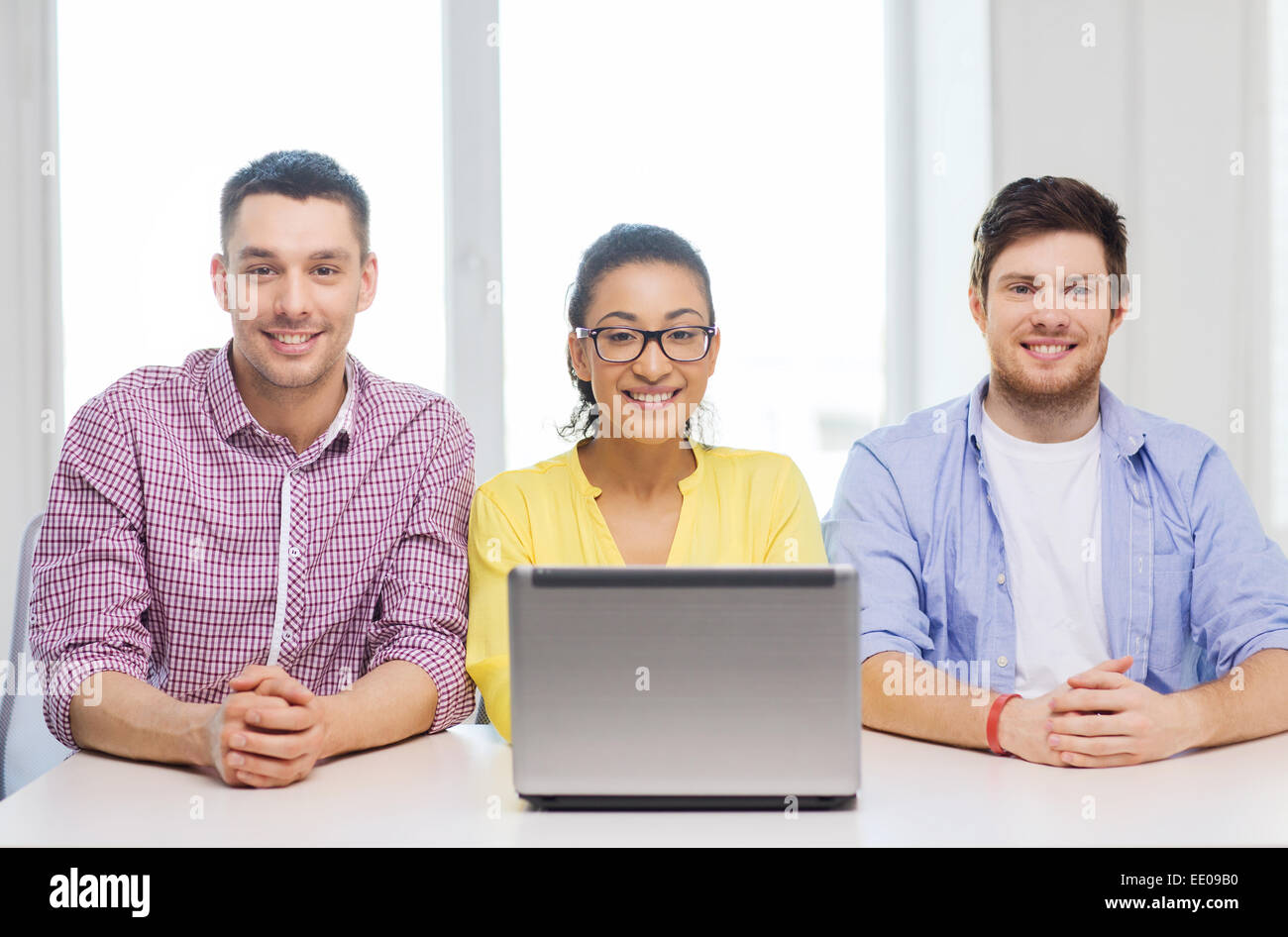 three smiling colleagues with laptop in office Stock Photo - Alamy