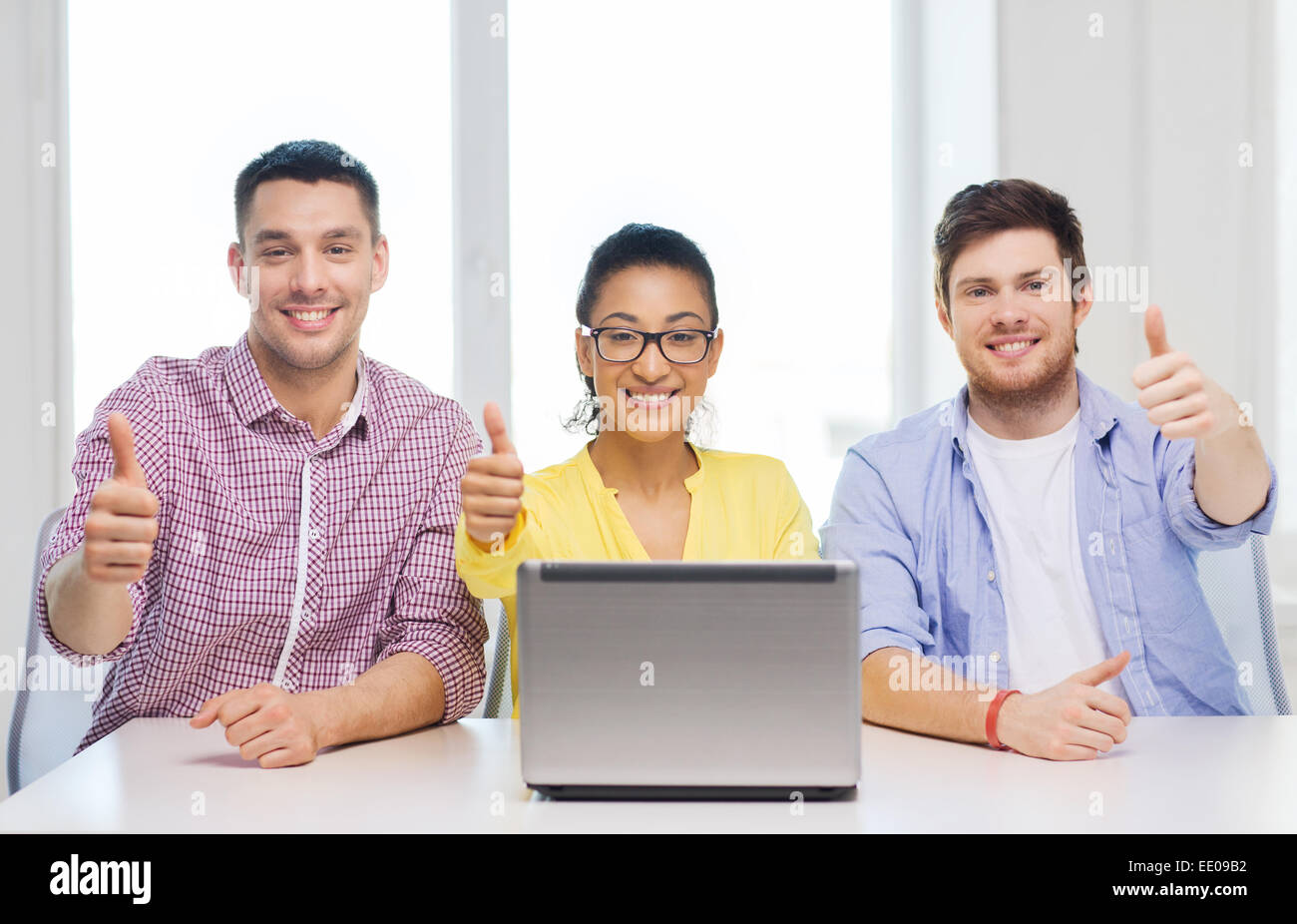 three smiling colleagues with laptop in office Stock Photo - Alamy