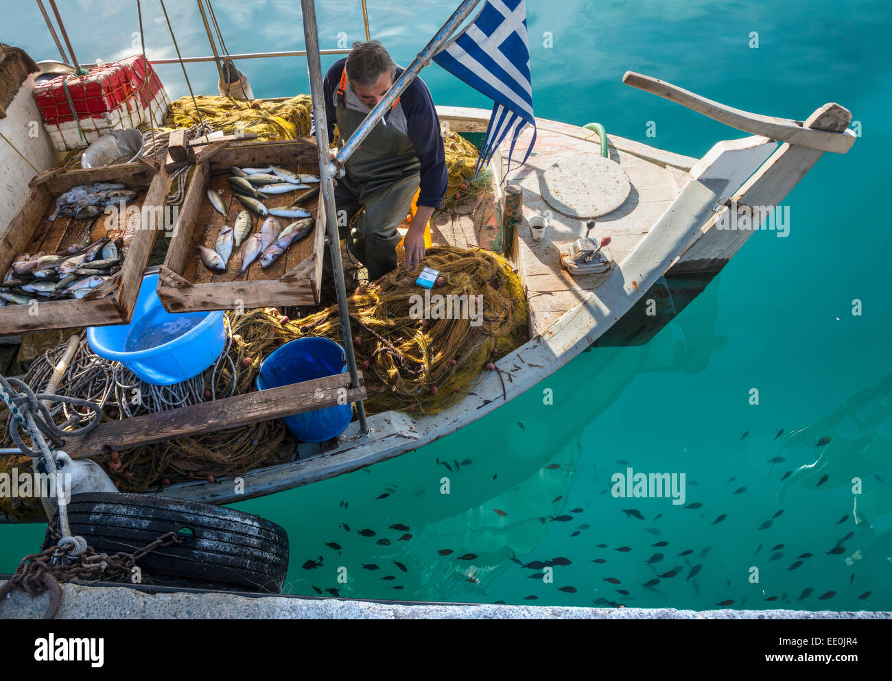 Fisherman selling his mornings catch from his boat in the harbour at ...