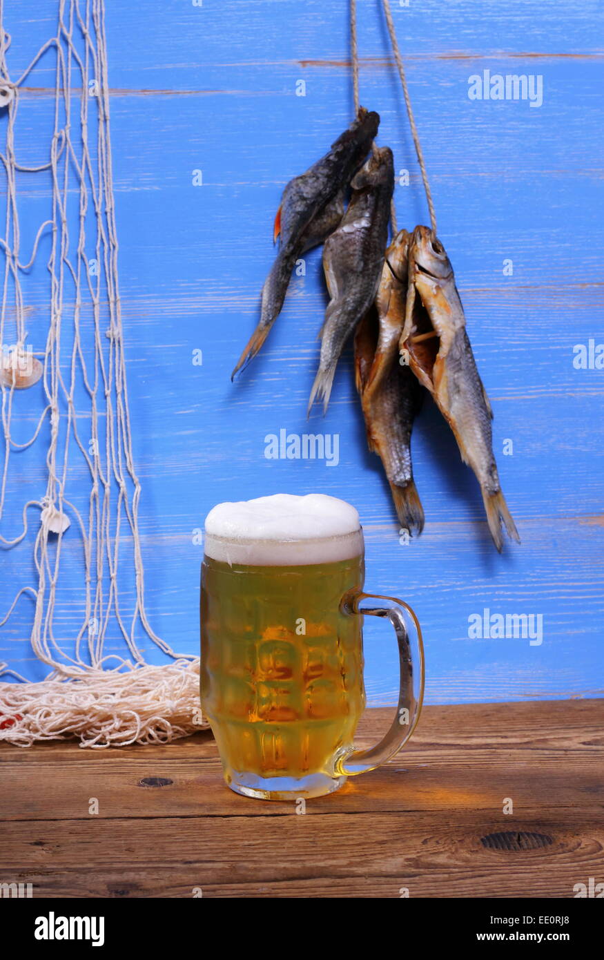Mug of beer on blue background, dried rudd fish and fishing net Stock ...
