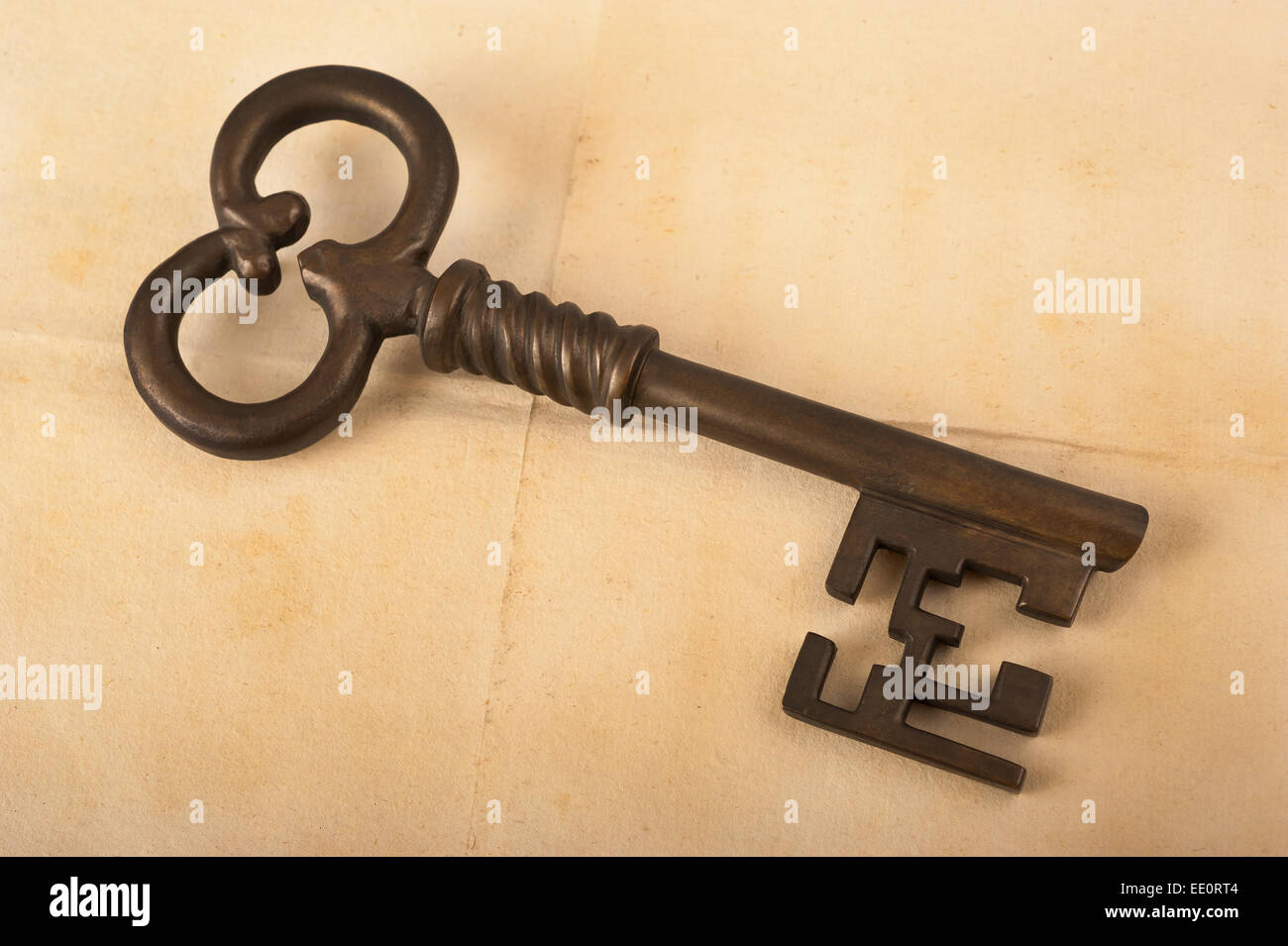 Old key on an antique parchment background Stock Photo - Alamy