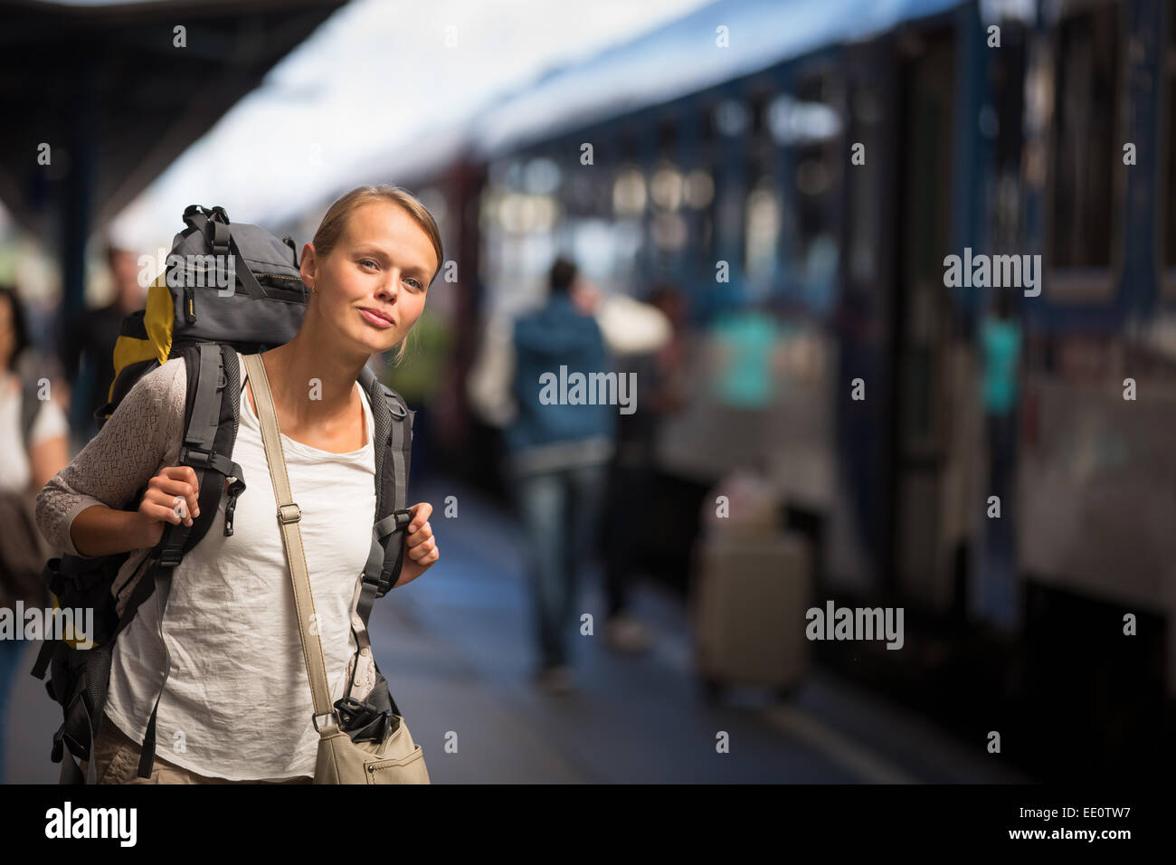 Pretty young woman boarding a train/having arrived to her destination ...