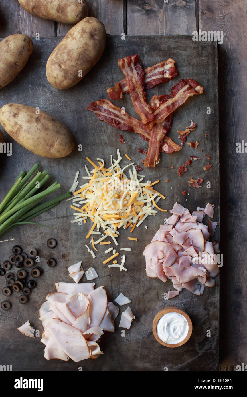 A deconstructed baked potato with bacon, ham, turkey, scallions, cheese, black olives and sour ...