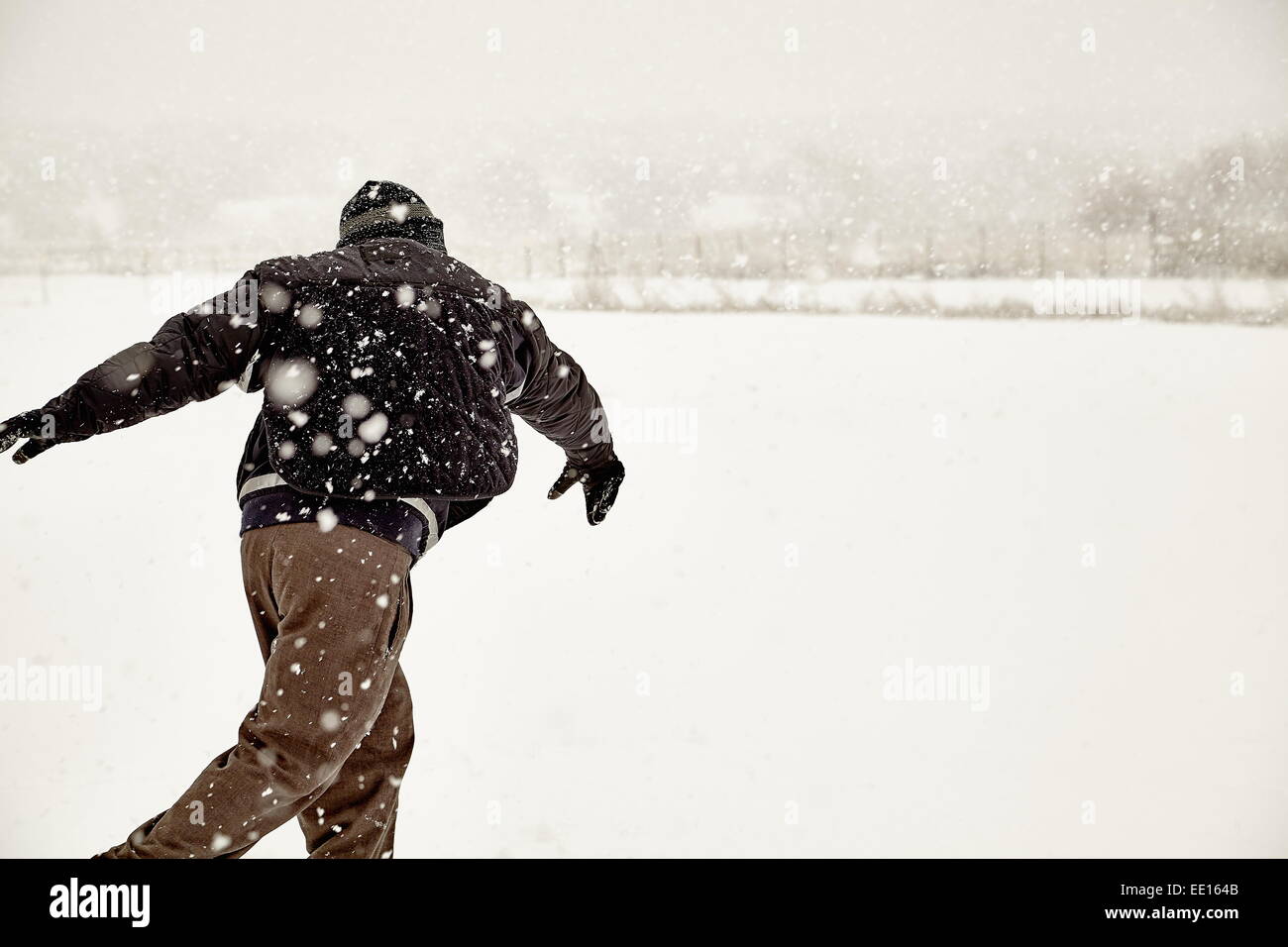 young adult in snow storm throwing a snowball Stock Photo - Alamy