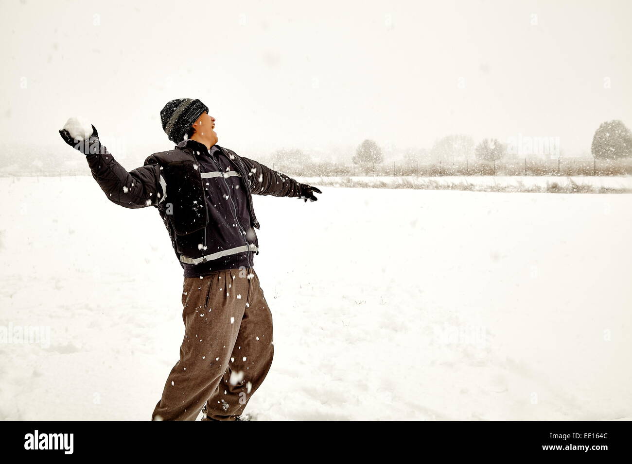 Young adult in snow storm throwing snowball and yelling Stock Photo - Alamy