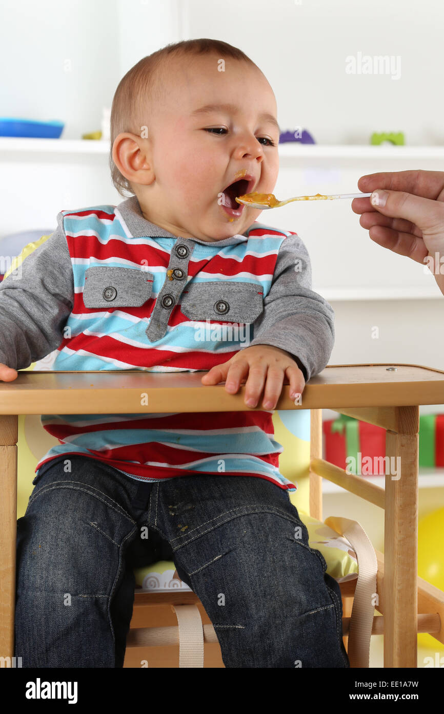 Hungry little baby child eating porridge food Stock Photo - Alamy