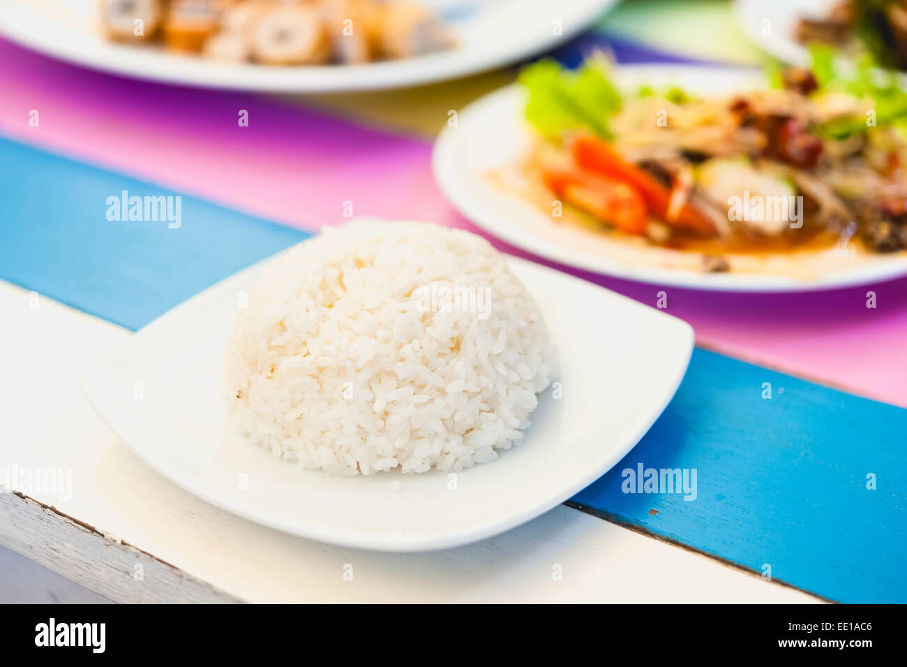Rice in a white disc on colorful wood table Stock Photo - Alamy