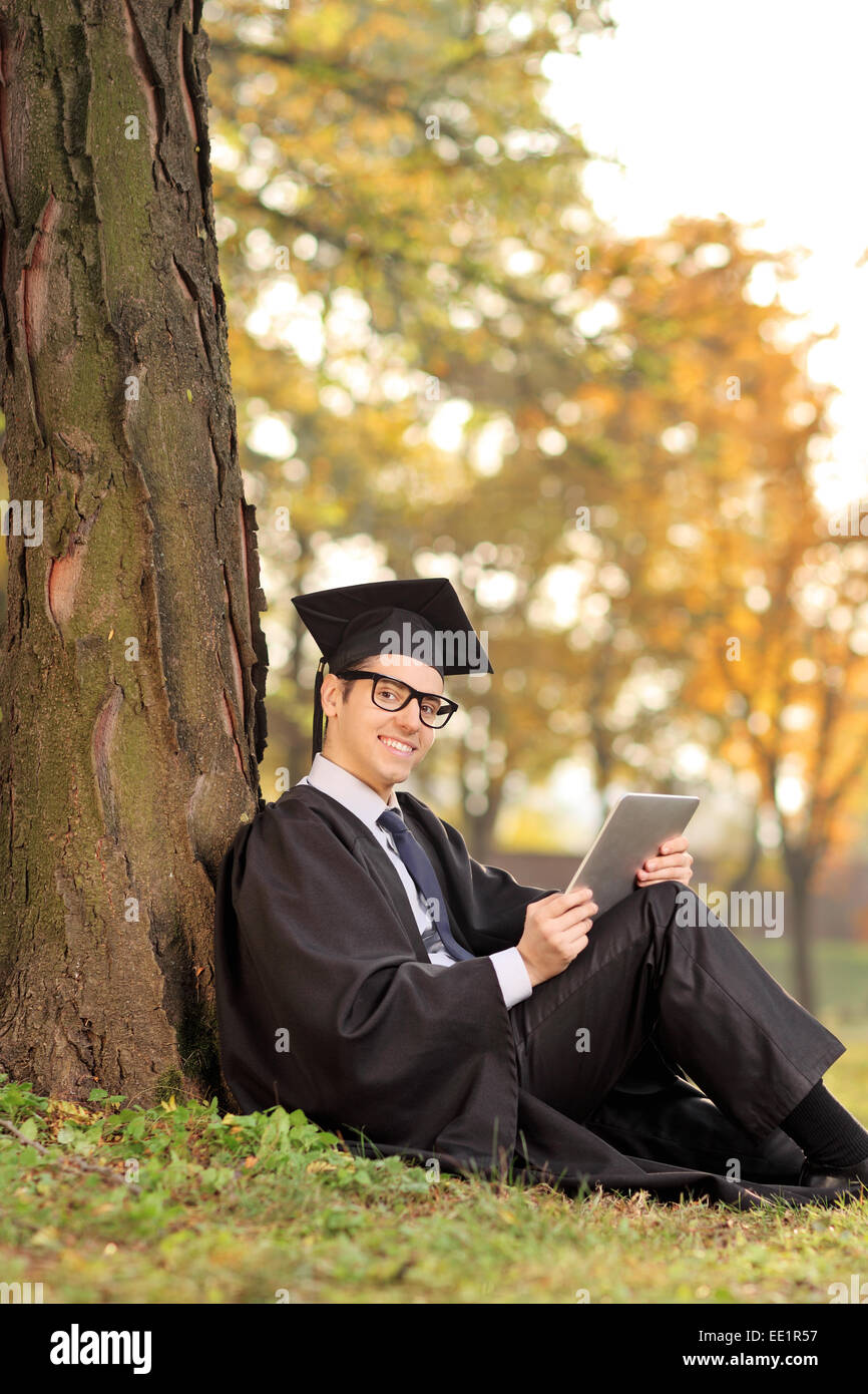 Graduate student holding a tablet in park and looking at the camera ...