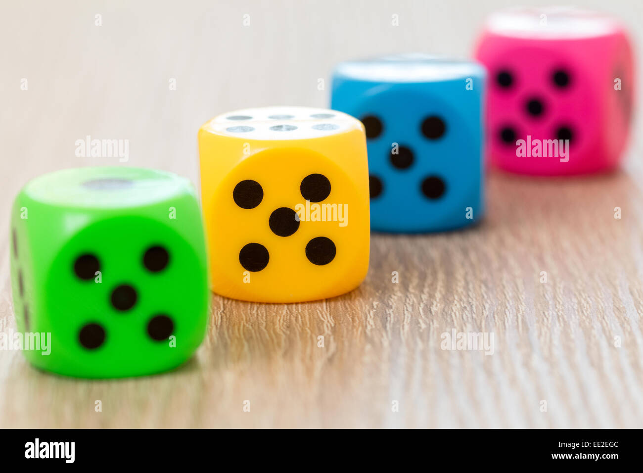 Four colorful dice on the wooden surface. Selective focus Stock Photo ...