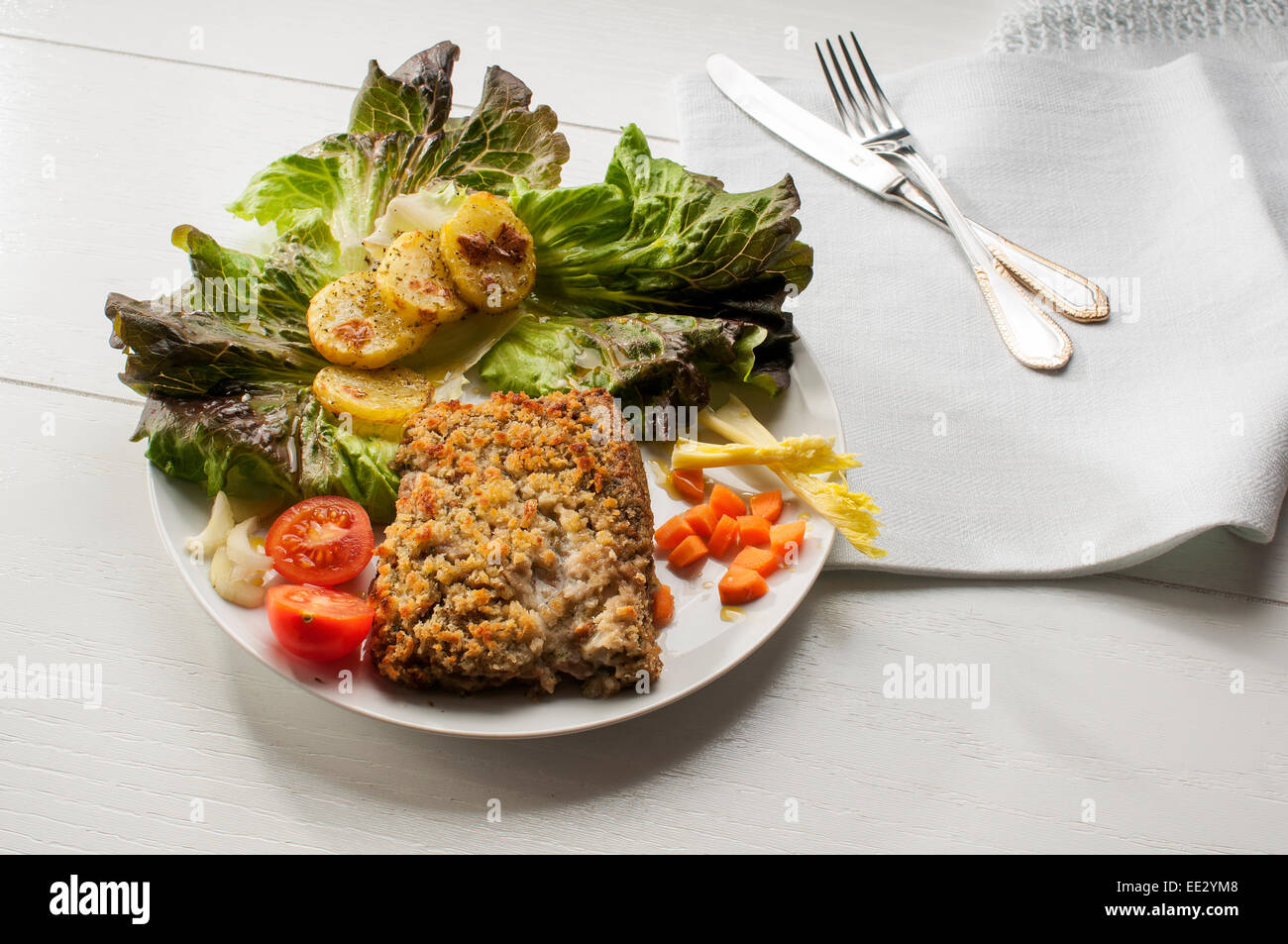 cod fillet breaded and baked with potatoes and salad as garnishing ...