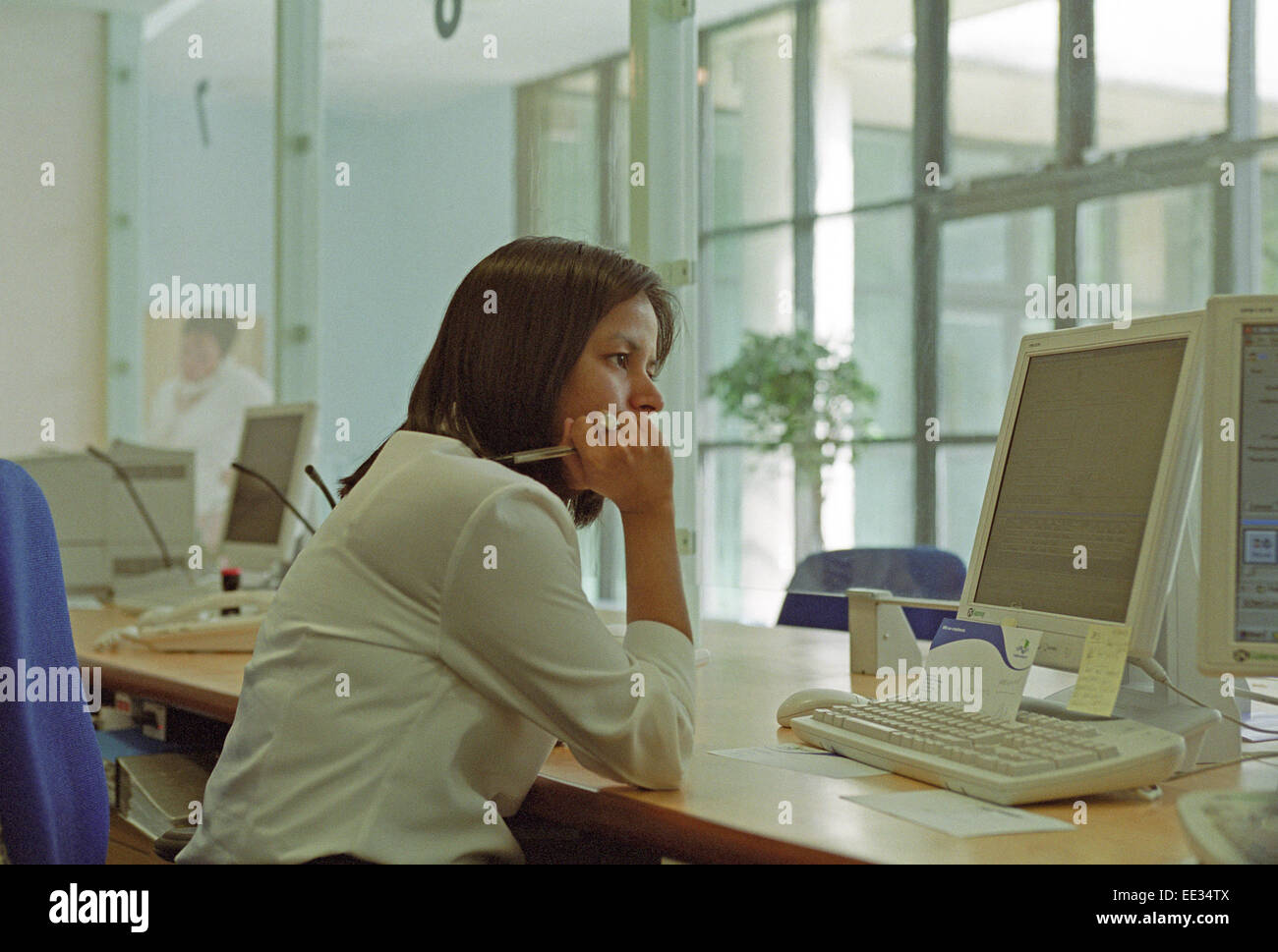 Female employee at computer behind counter in council information ...