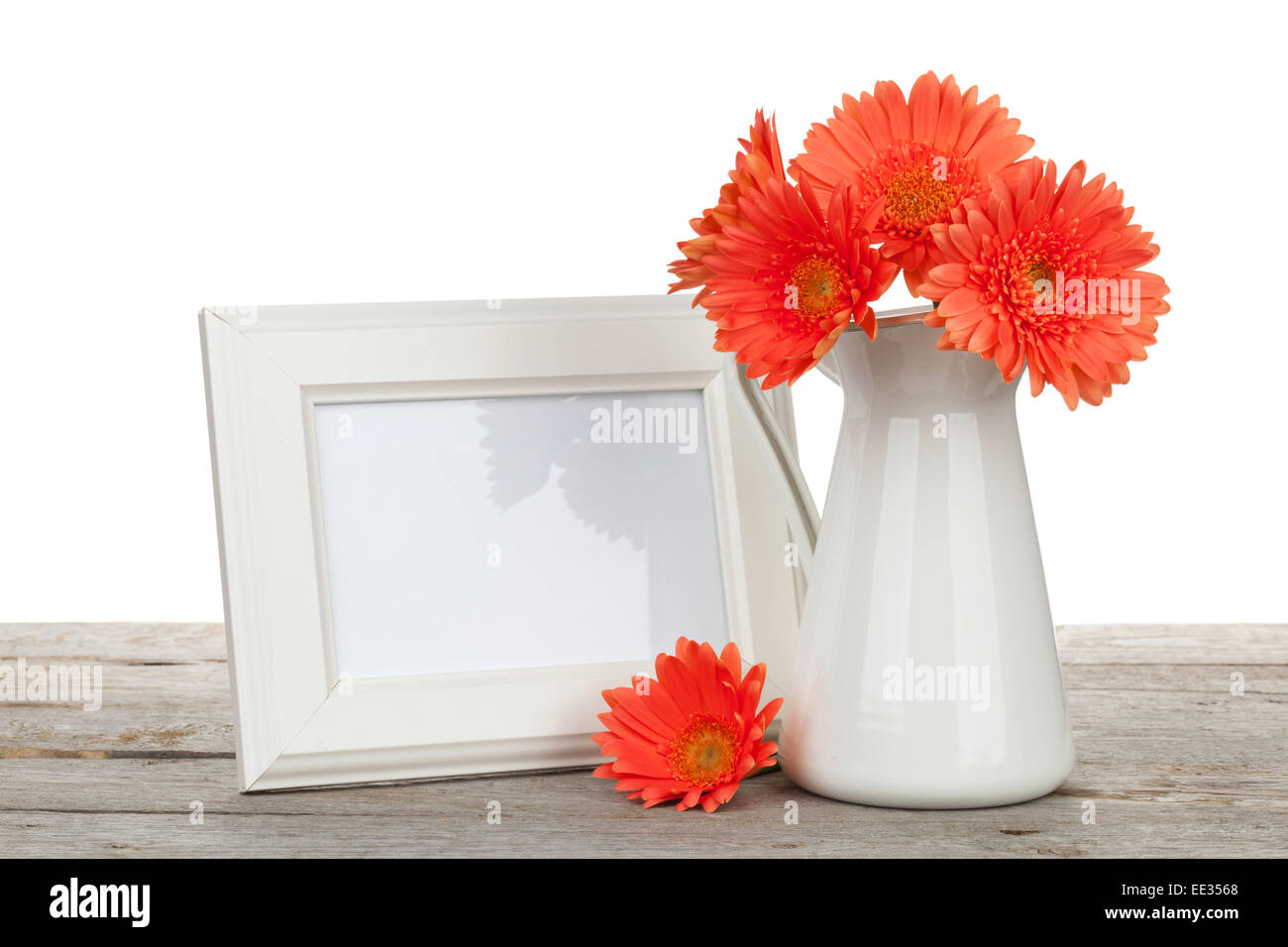 Orange gerbera flowers and photo frame on wooden table on white ...