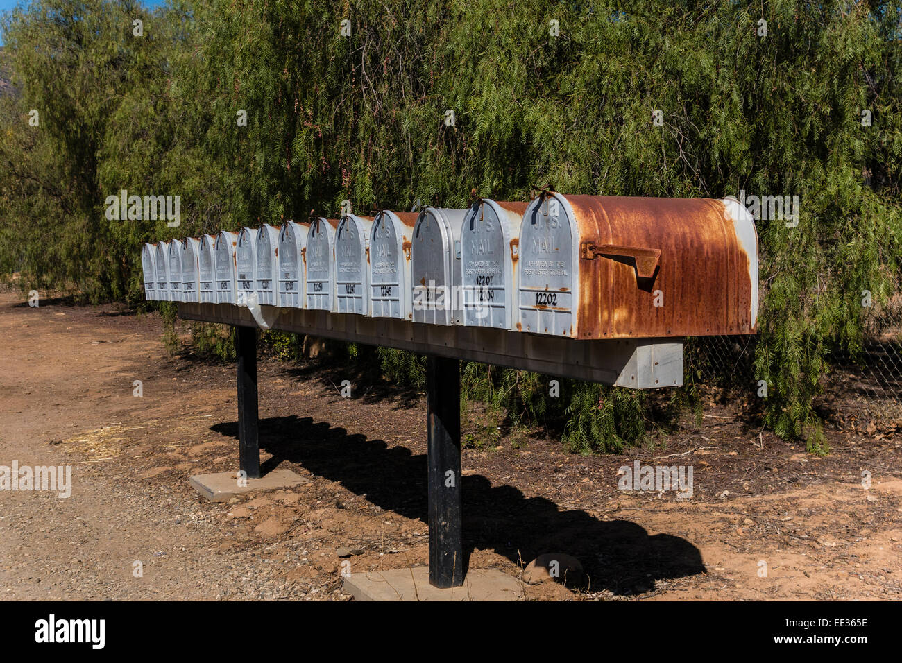 A row of identical rusting metal boxes along a country road outside of ...