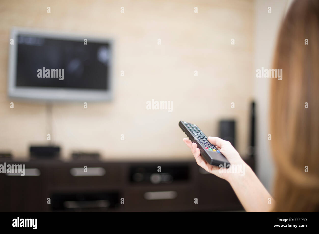 Young woman changing channels with remote control Stock Photo - Alamy