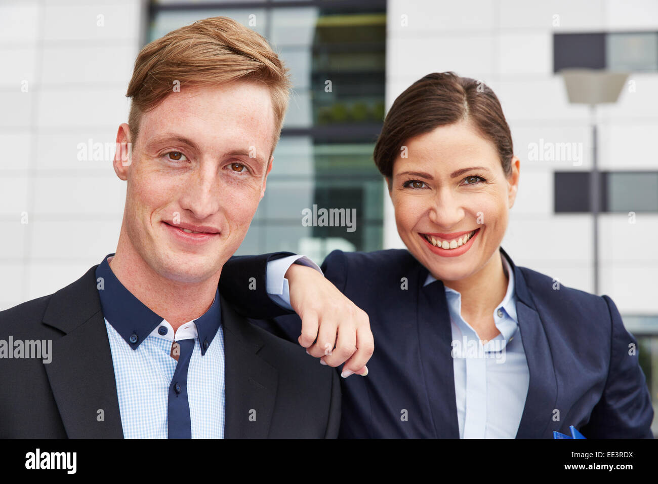 Portrait of two happy business consultant people in front of office ...