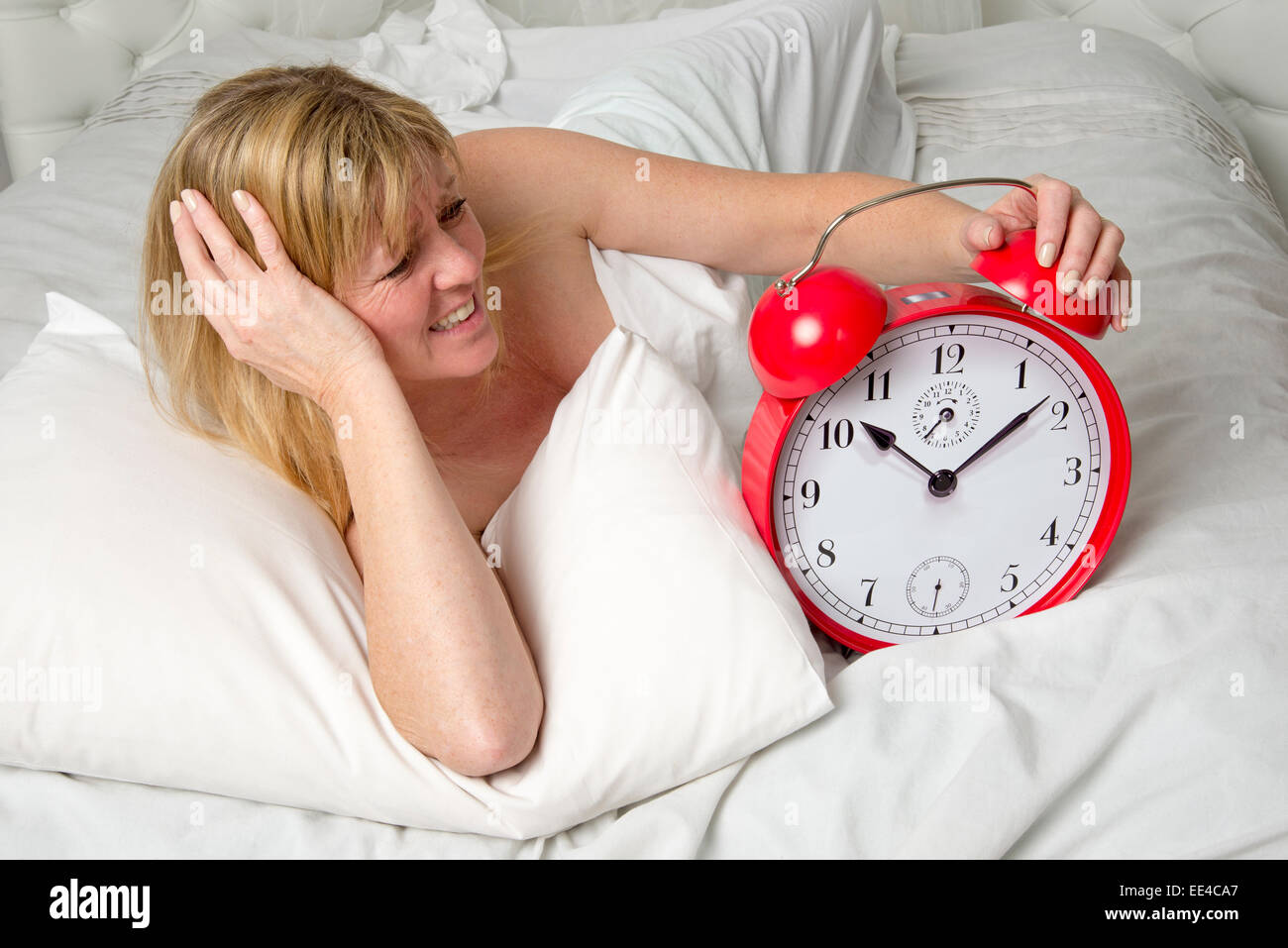 Woman in bed and getting angry with ringing alarm clock Stock Photo - Alamy