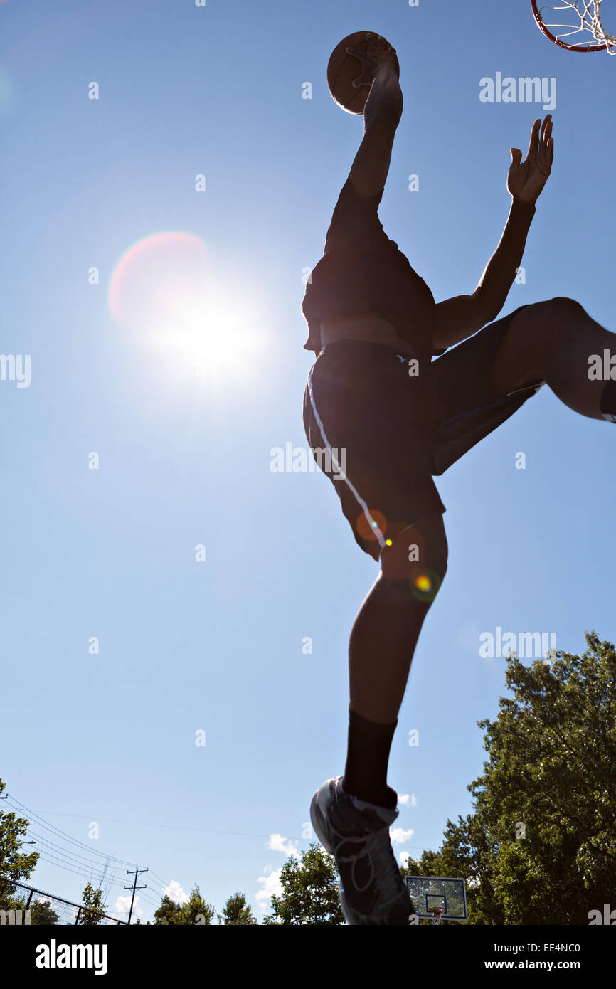 Young basketball player driving to the hoop for a high flying slam dunk ...