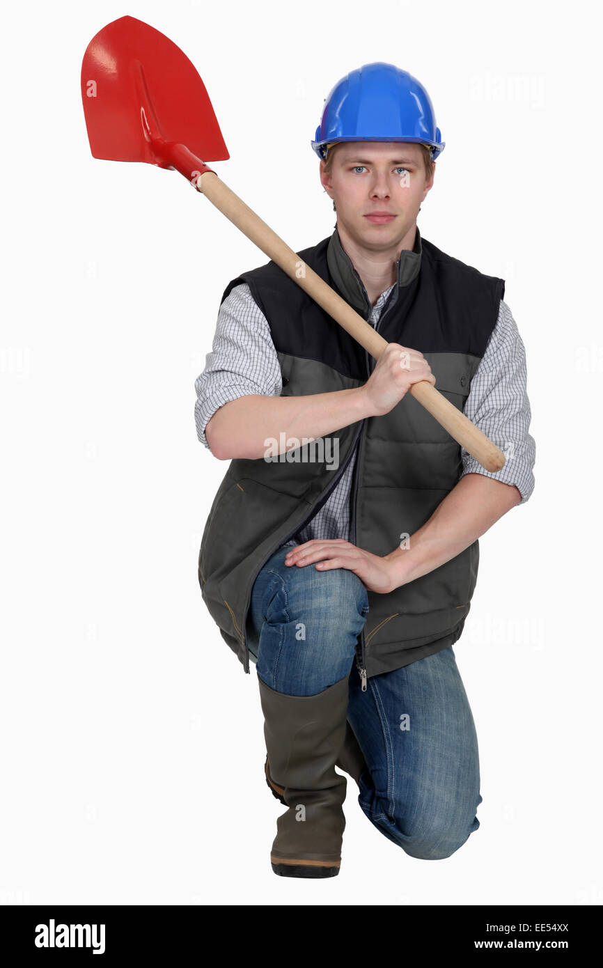 Man with spade kneeling Stock Photo - Alamy
