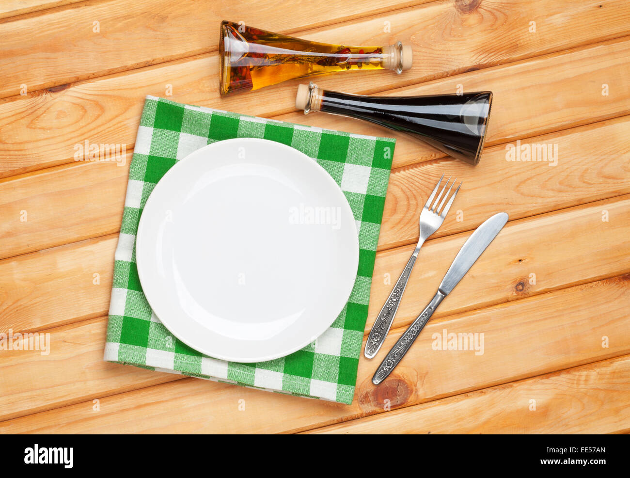 Empty plate, silverware and towel over wooden table background. View ...