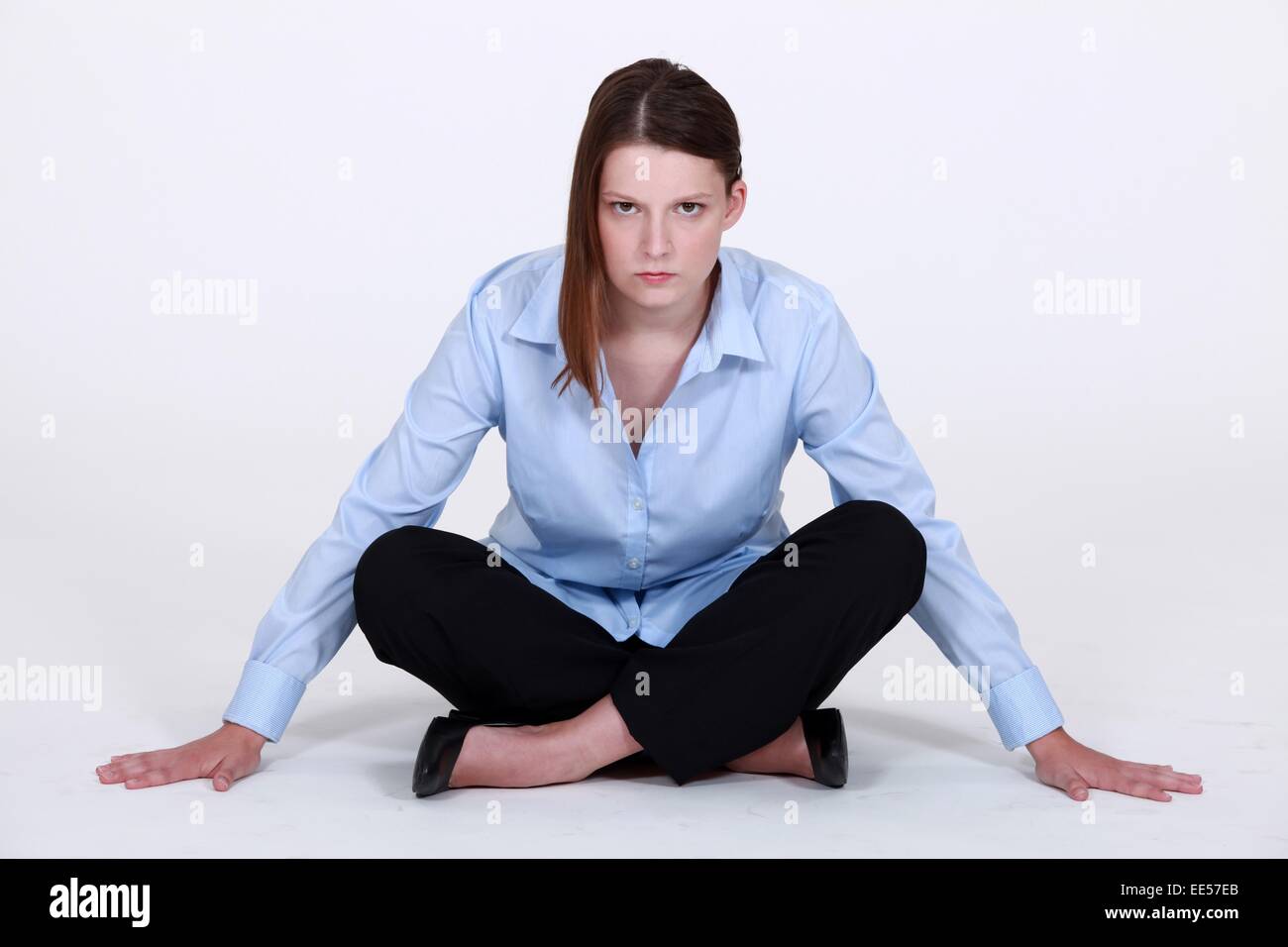 Stern businesswoman sitting cross legged Stock Photo - Alamy