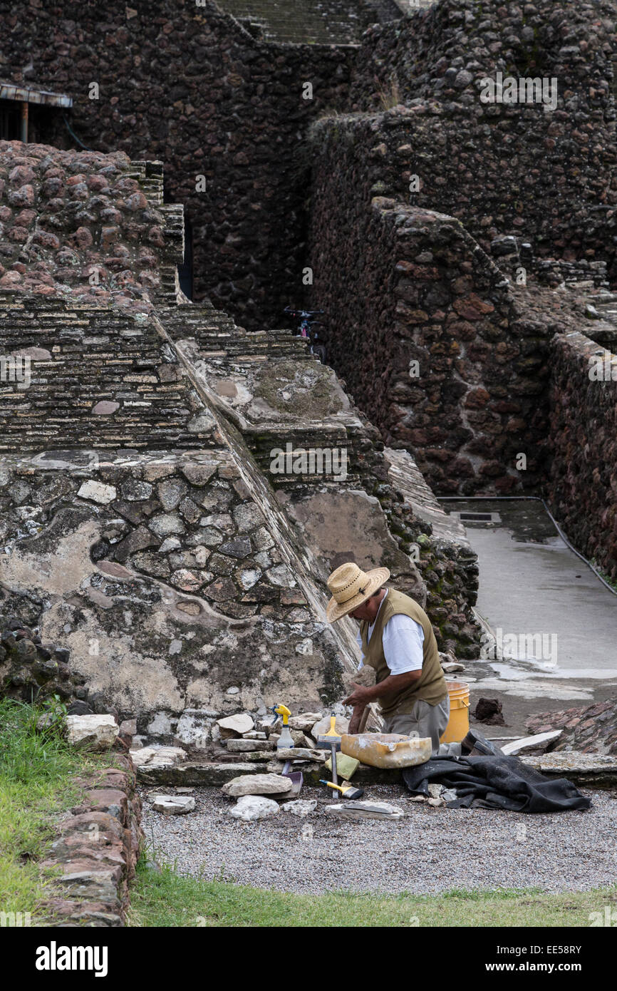 A worker cleaning & repairing stonework at the Great Pyramid of Cholula ...