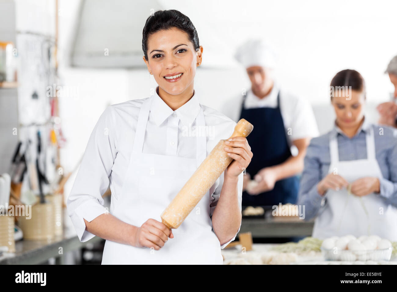 Smiling Chef Holding Rolling Pin While Colleagues Preparing Past Stock ...