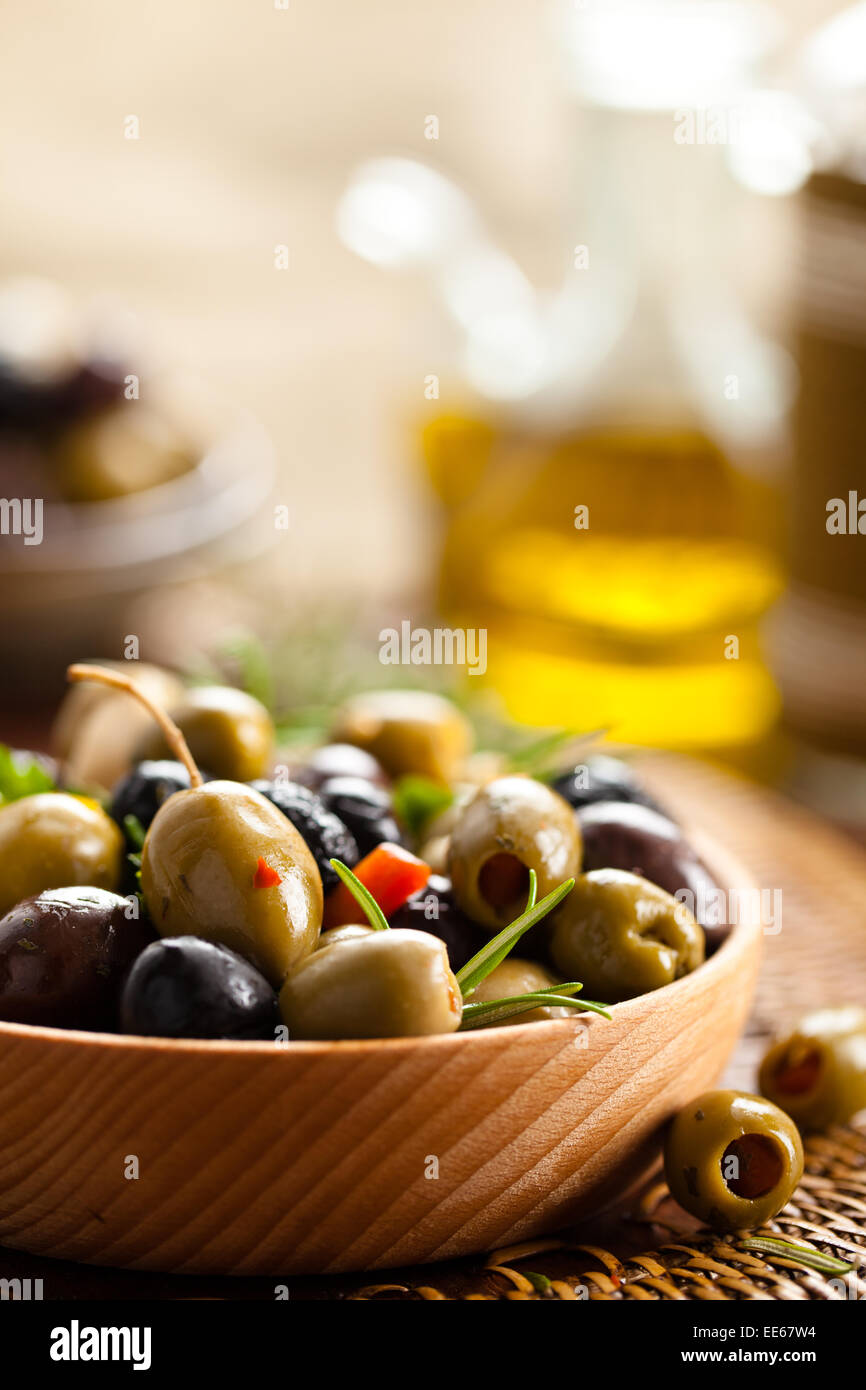 Close-up shot of marinated olives with herbs and spices in wooden plate ...