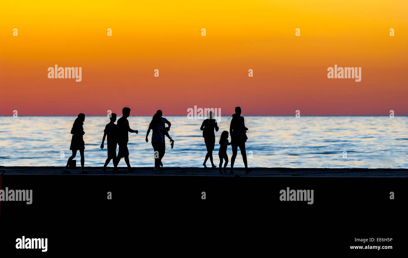 A sunset silhouette of a family going home from a day at Lake Michigan ...