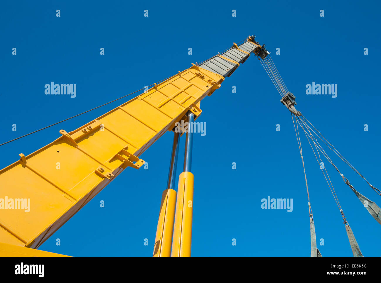 Large extended industrial crane jib boom arm against a blue sky ...
