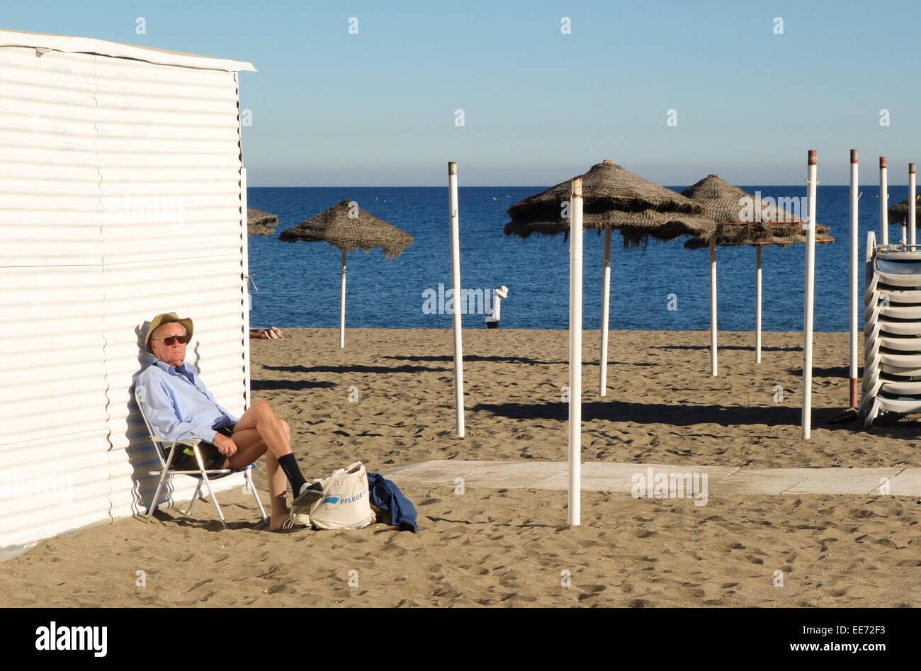 Man, tourist on mediterranean empty beach in winter sunbathing. Costa ...