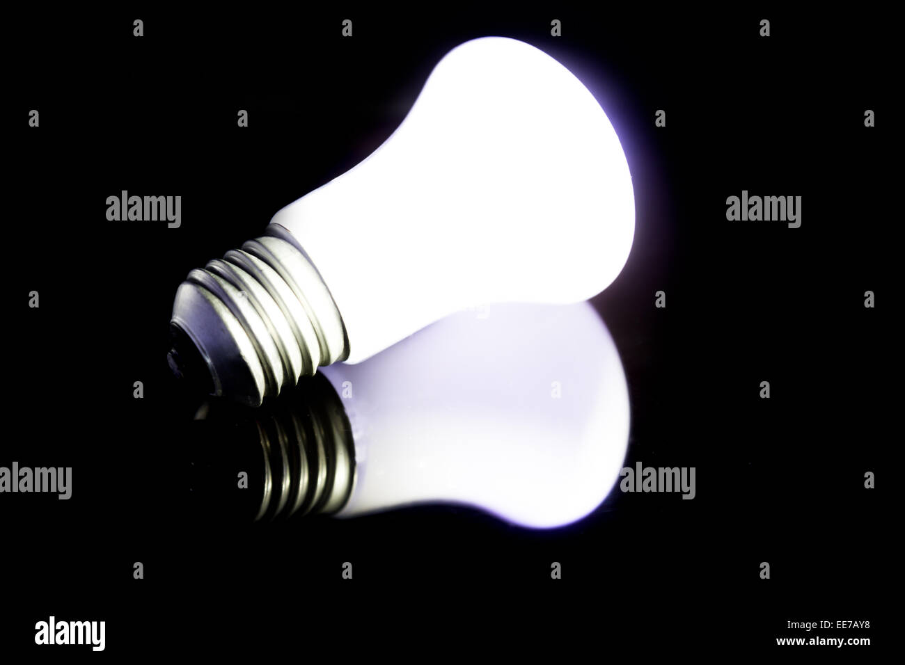 Glowing halogen bulb not in socket, with reflection on black surface ...