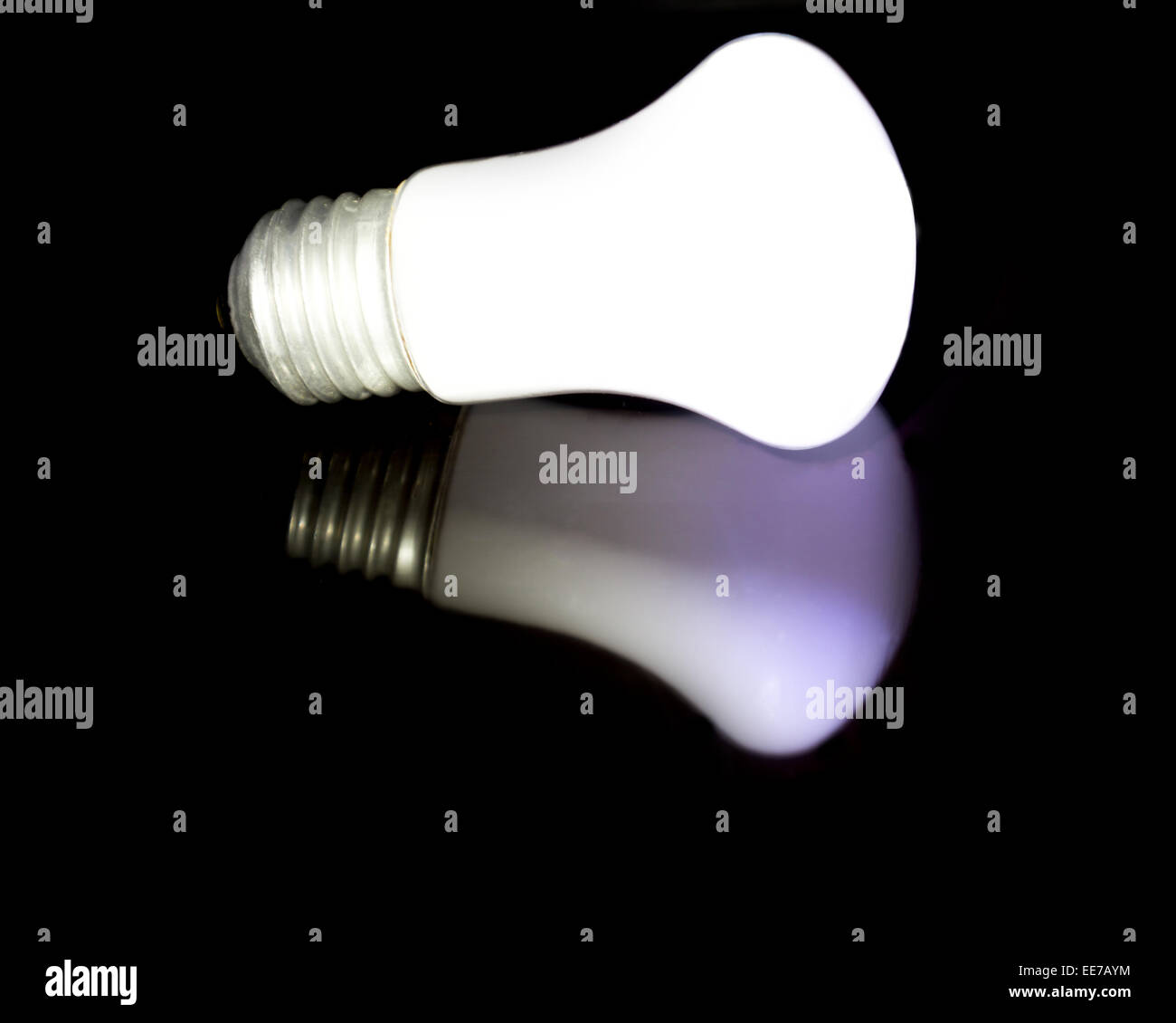 Glowing halogen bulb not in socket, with reflection on black surface ...