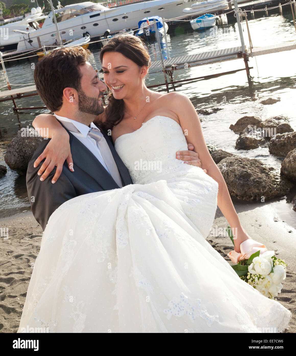Married couple in day of their wedding. Bride in the arms of her ...