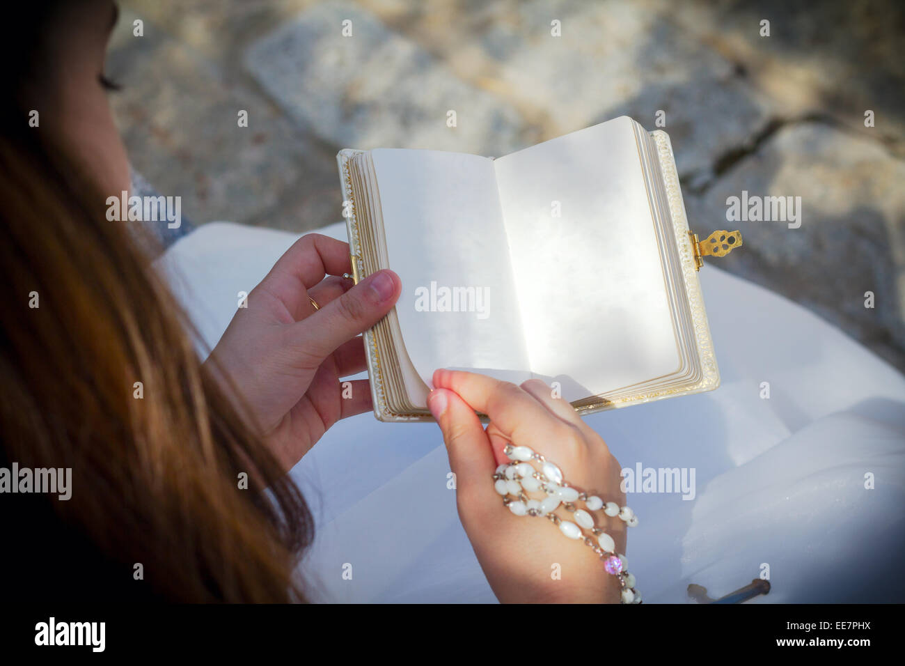 Young girl reading a prayer book with blank copy space in her First ...