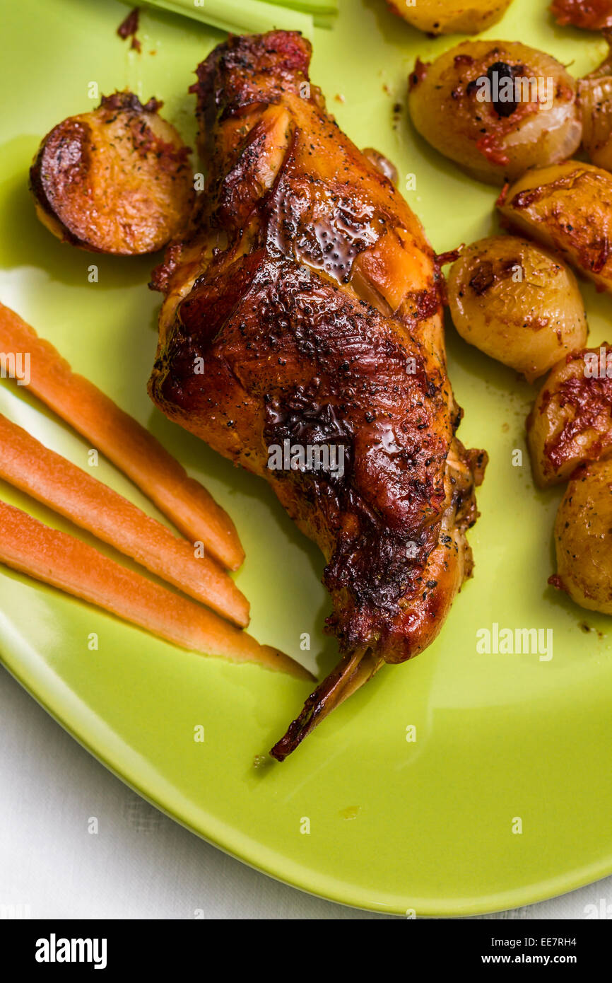Plate with roasted rabbit leg and vegetable garnish in restaurant ...