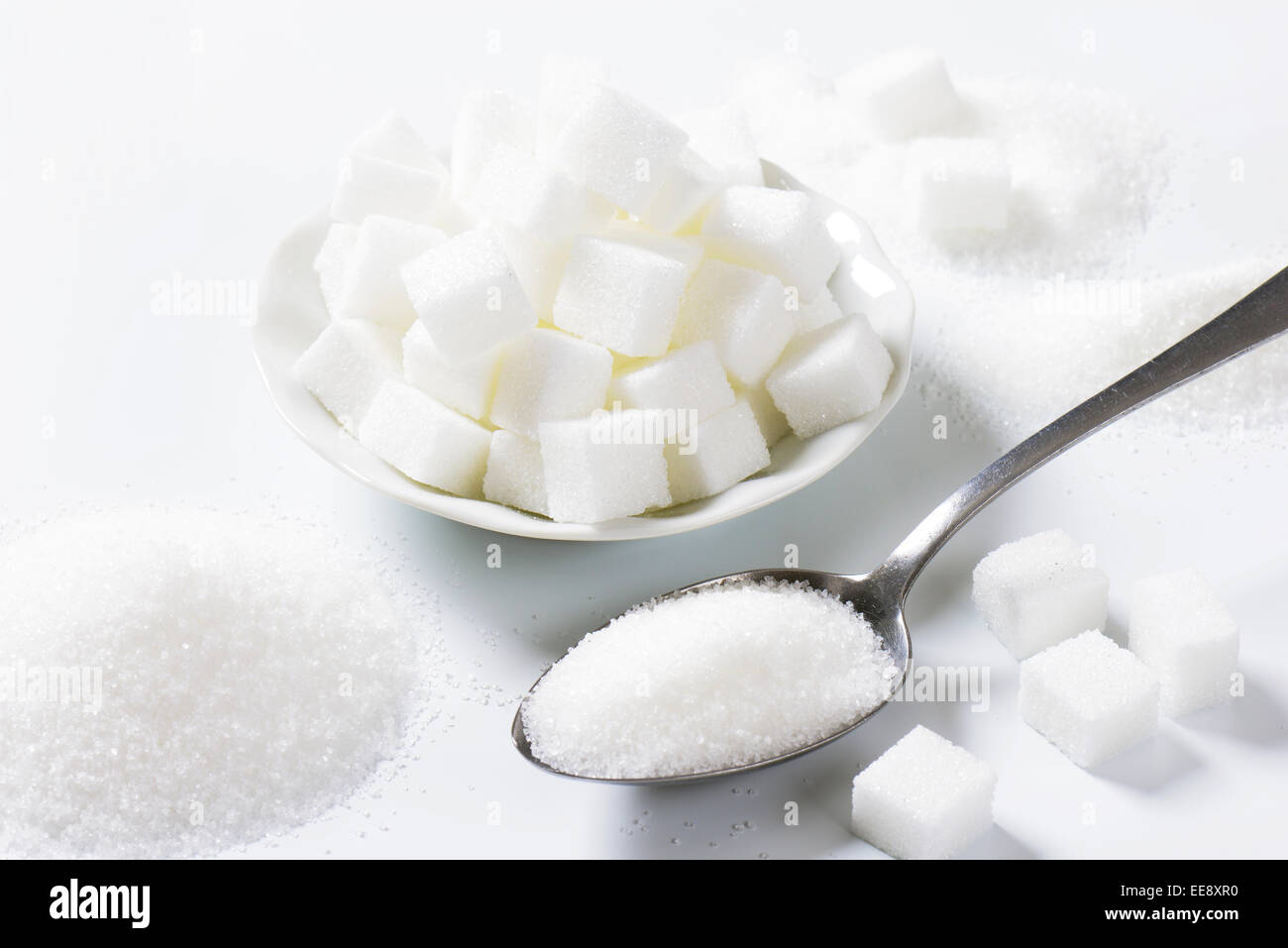 Spoonful of fine granulated sugar and pile of sugar cubes Stock Photo ...