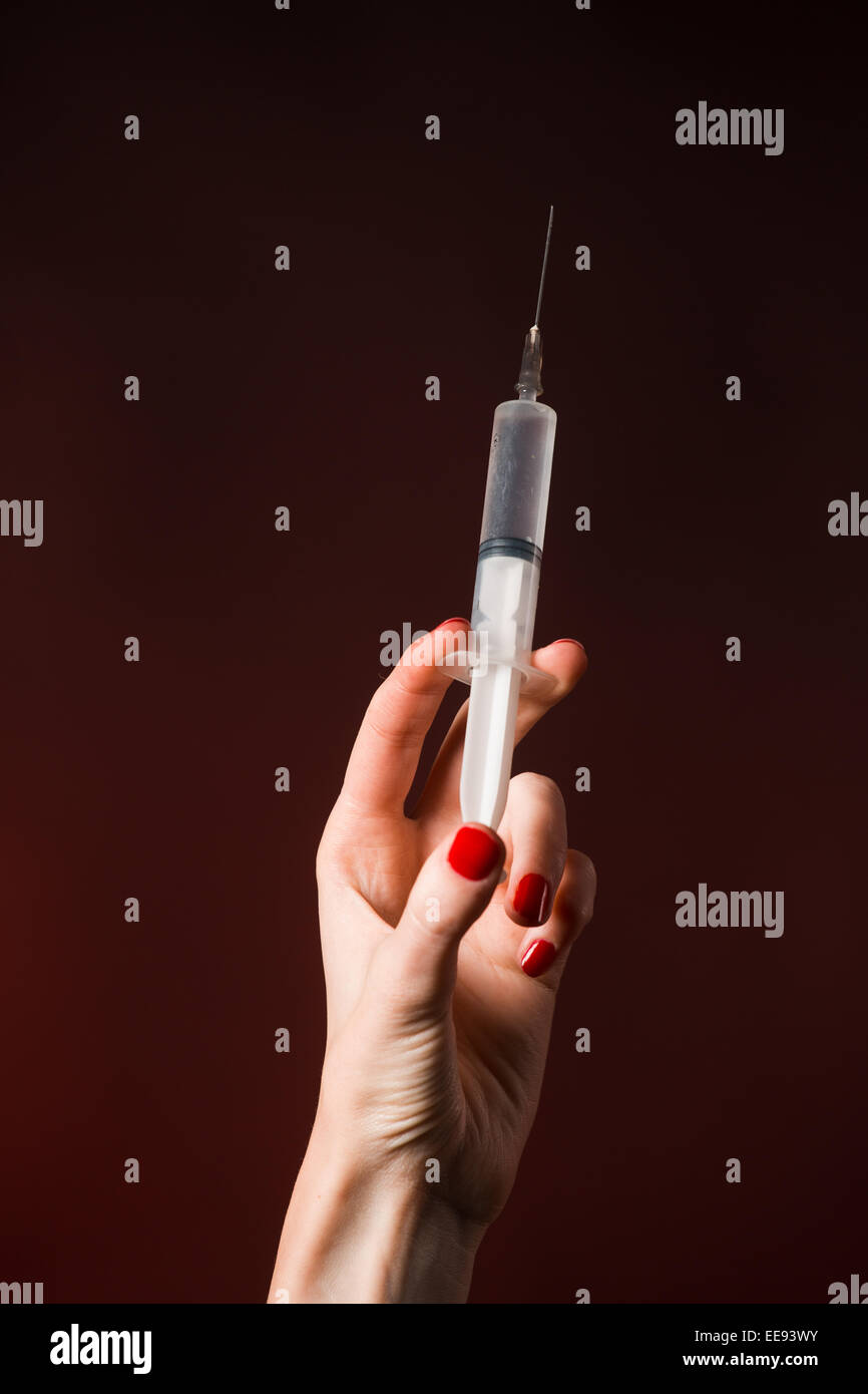 A syringe in a hand is isolated on black background Stock Photo - Alamy